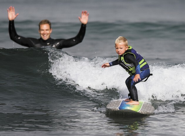 Three-year-old surfer kid rides waves and gives high five