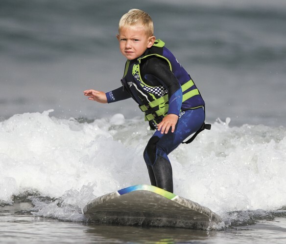 Three-year-old surfer kid rides waves and gives high five